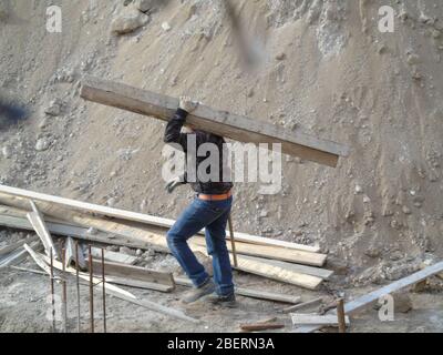 Worker handling wooden axis in a construction site Stock Photo - Alamy