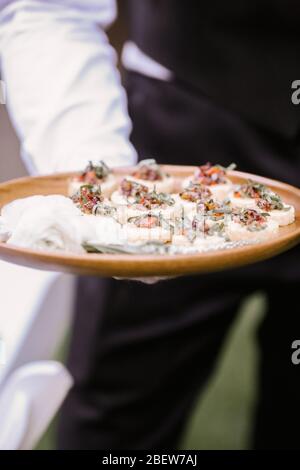 Appetizers on wood tray in server's hand at formal event Stock Photo ...
