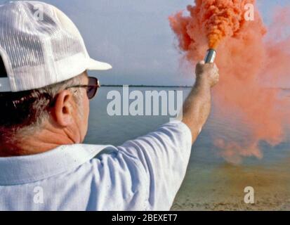 Man holding a lit flare for rescue patrol to find him ca. 1980 Stock ...