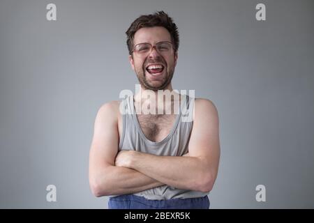 Untidy dressed man in big glasses smiling going crazy of self isolation ...