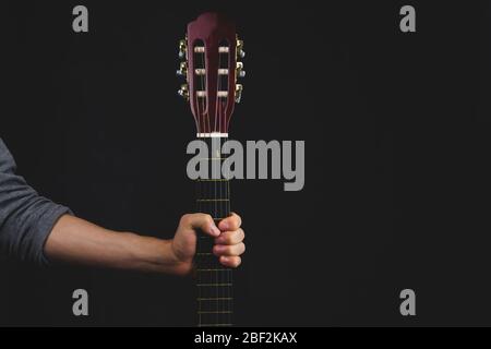 Hand holds acoustic guitar. musical instrument on black background ...