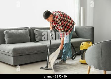 Young Asian man hoovering floor at home Stock Photo - Alamy