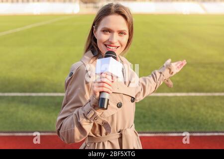 Beautiful reporter with microphone at the stadium Stock Photo - Alamy