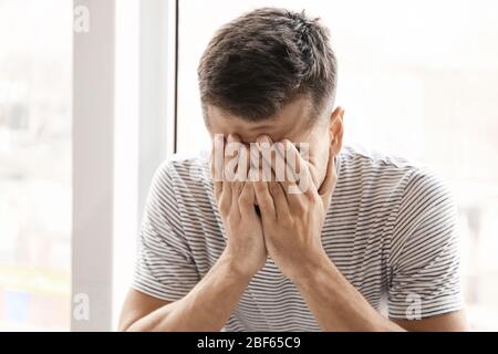 Depressed young man near window Stock Photo - Alamy