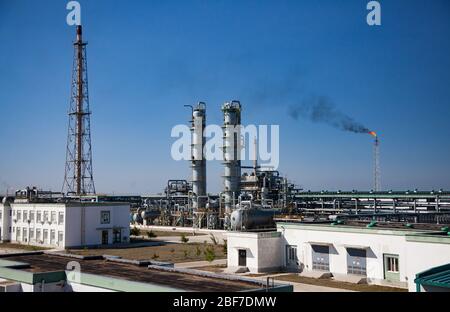 Distillation towers, burning gas torch, pipelines and industrial buildings on clear blue sky ...
