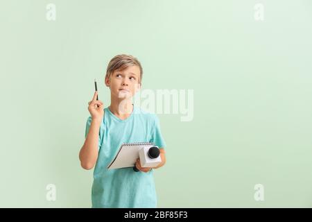 Little journalist with microphone and notebook on white background ...