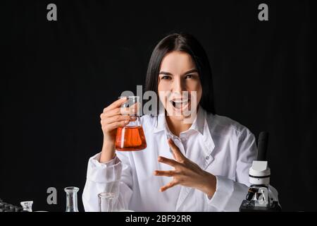 Crazy female alchemist with potion on dark background Stock Photo - Alamy