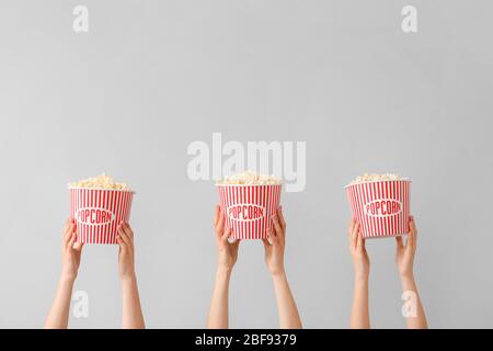 Many hands with popcorn in buckets and cups of drink on white ...