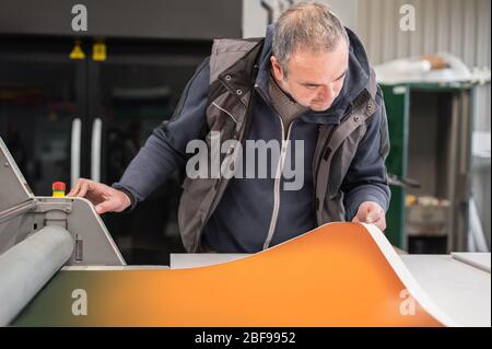 Worker printmaker technician operator works in large digital printing ...
