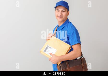 Postman with letters on light background Stock Photo - Alamy