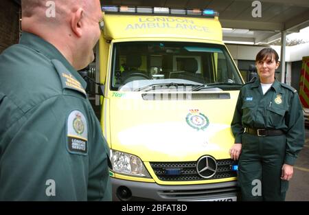 An ambulance technician and paramedic wait in front of an ambulance ...