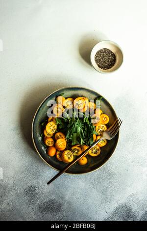 Healthy salad with rocket herb, kumquat fruits and chia seeds on stone ...