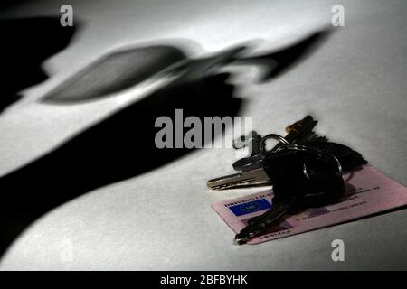 The shadow of a man drinking alcohol with his driving licence and car ...