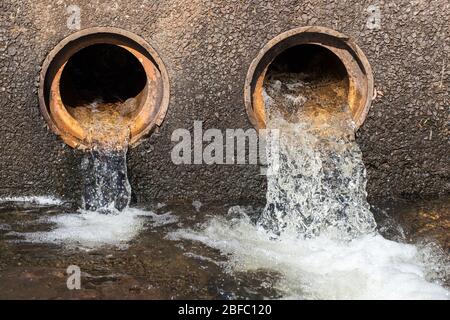 Water flowing from pipes under causeway on road Stock Photo - Alamy