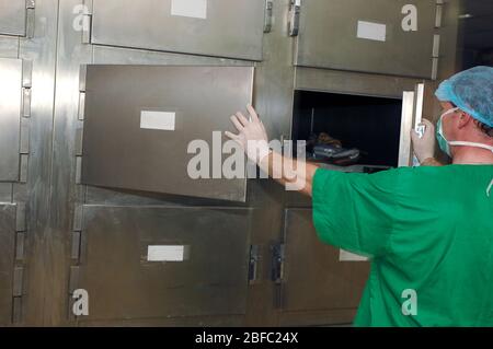 A mortuary technician removes a human body from a cold storage facility ...