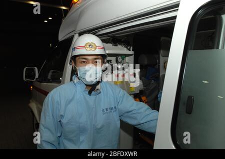 A Japanese paramedic, masked and wearing a white 'hard hat' standing by ...
