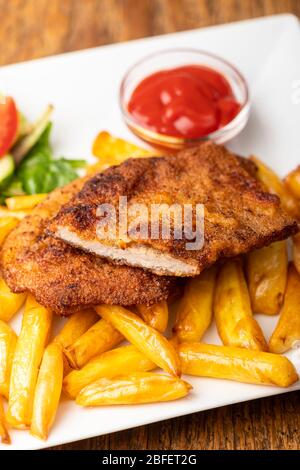 Delicious cut schnitzel with french fries and microgreens on white ...
