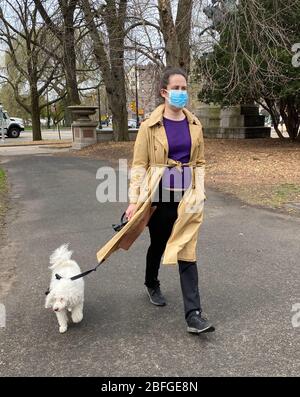 A woman in a medical mask walks in the autumn park. The woman is very ...