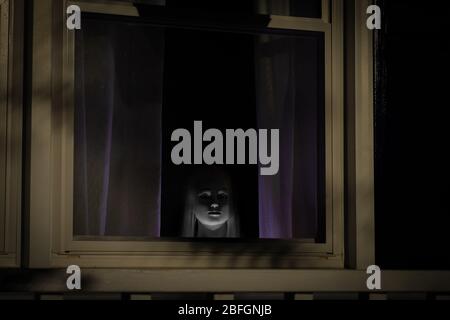 A mannequin head looks like a real little girl peering out a screened ...