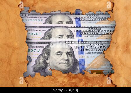 Dollars through torn craft paper Stock Photo - Alamy