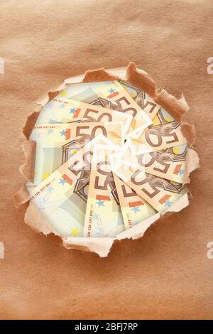 Euro banknotes through torn craft paper Stock Photo - Alamy