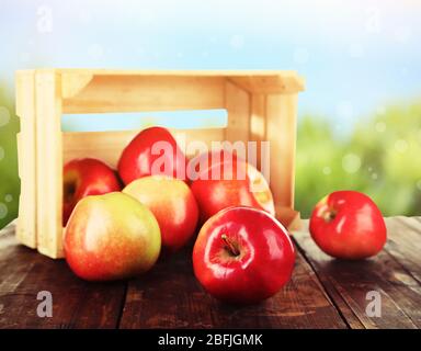 Spilled red apples near crate on nature background Stock Photo - Alamy