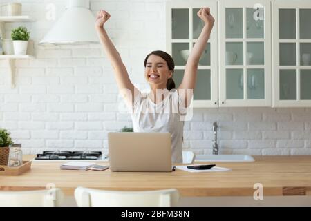 Young woman exulting using calculator and laptop for calculating ...