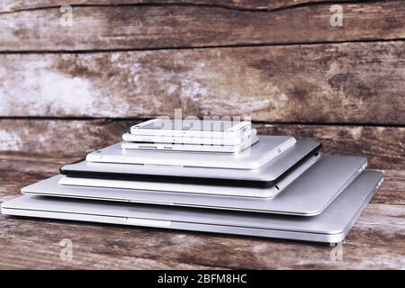 Pile of different modern electronics gadgets on old wooden background ...