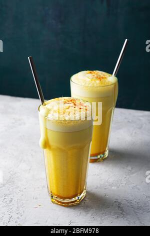 Saffron latte in a glass cup on concrete background,metal straw,dry ...