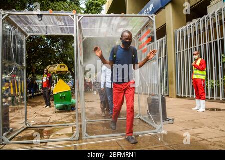Passengers pass through a sanitiser spray booth that disinfects the ...