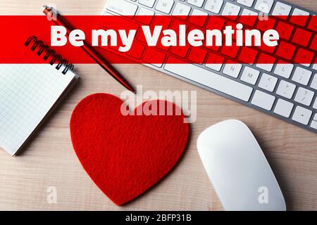 Computer peripherals with red heart, pen and notebook on light wooden ...