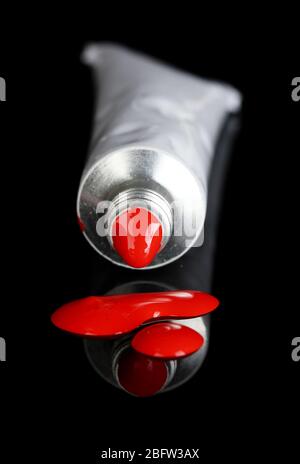 Red paint follows from the tube on black background close-up Stock ...