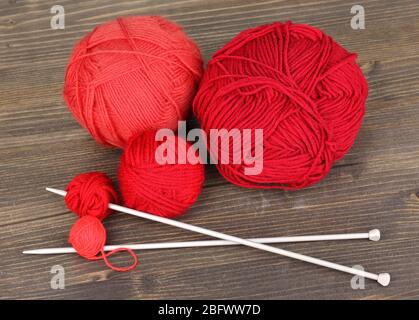 Red knittings yarns on wooden table on green background Stock Photo - Alamy