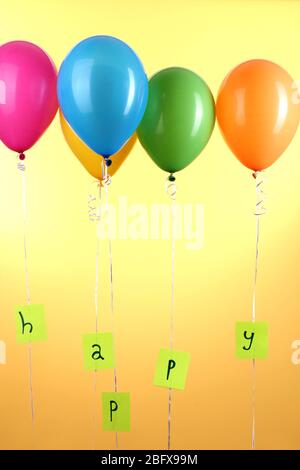 Colorful balloons keeps word happy on yellow background Stock Photo - Alamy