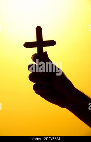 man hand with crucifix, on yellow background Stock Photo - Alamy