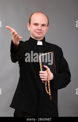 Young pastor with rosary and Bible, on gray background Stock Photo - Alamy