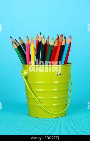 Colorful pencils in pail on table on green background Stock Photo - Alamy