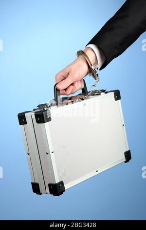 Hand with handcuff and suitcase, on color background Stock Photo - Alamy