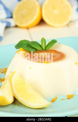 Lemon Panna Cotta with orange zest and caramel sauce, on color wooden ...
