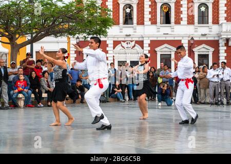 Dancers in costume performing Festejo traditional Afro-Peruvian dance to crowds in the main ...