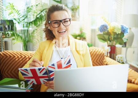 Young woman with UK flag and laptop on light blue background with space ...