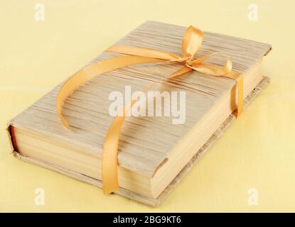 Book wrapped with color ribbon, on wooden background Stock Photo ...
