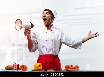 Young chef shouting loudly into megaphone Stock Photo - Alamy