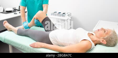 Osteopath doing a diagnosis of a woman's leg. Woman may have a broken ...