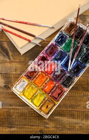 Composition with colorful watercolors, brushes and sketcher on wooden ...