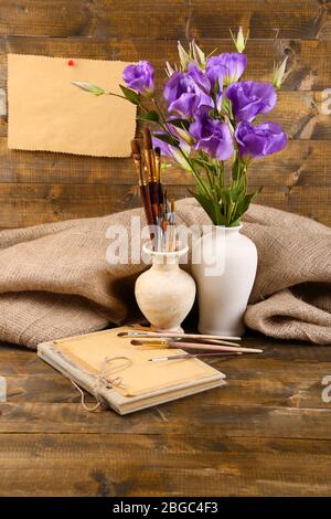 Composition with colorful watercolors, brushes in vase and sketcher on ...