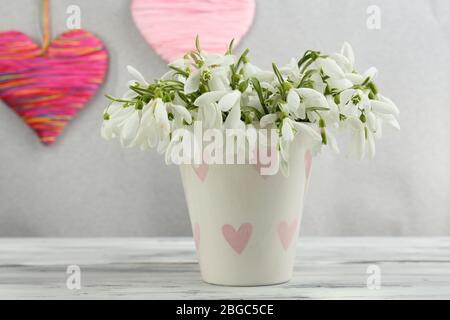 Beautiful snowdrops in vase with hearts on grey background Stock Photo ...