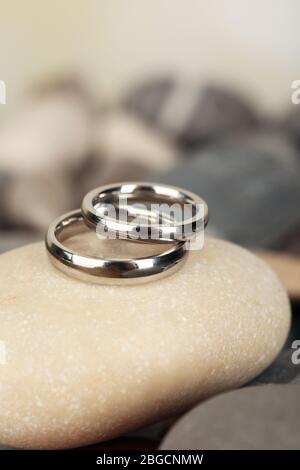 Wedding rings on rocks on bright background Stock Photo - Alamy