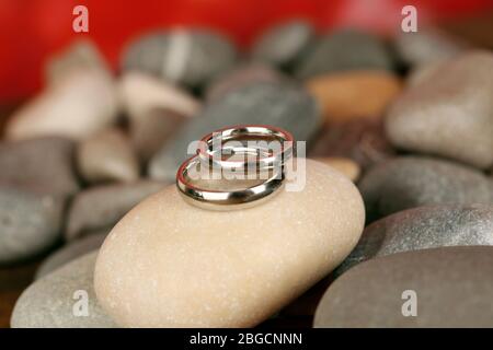 Wedding rings on rocks on red background Stock Photo - Alamy