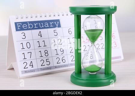 Hourglass and calendar on bright background Stock Photo - Alamy